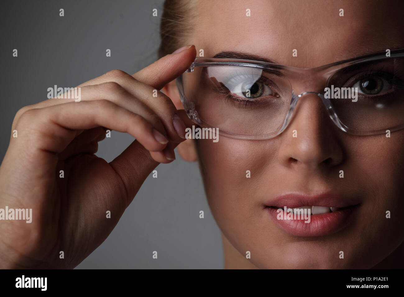 Beautiful woman with transparent futuristic glasses on gray background ...