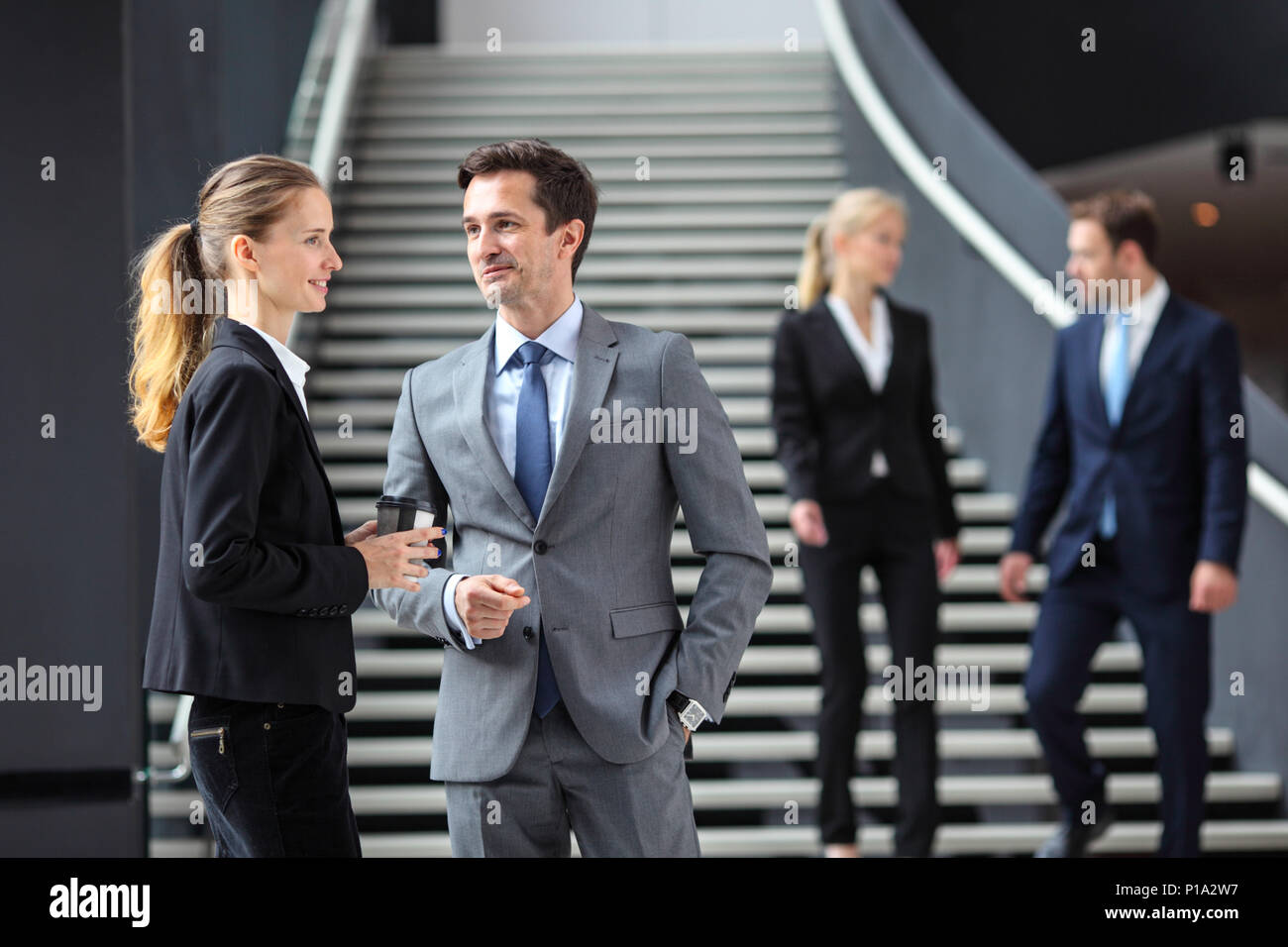 Business people standing in office lobby and talking Stock Photo - Alamy