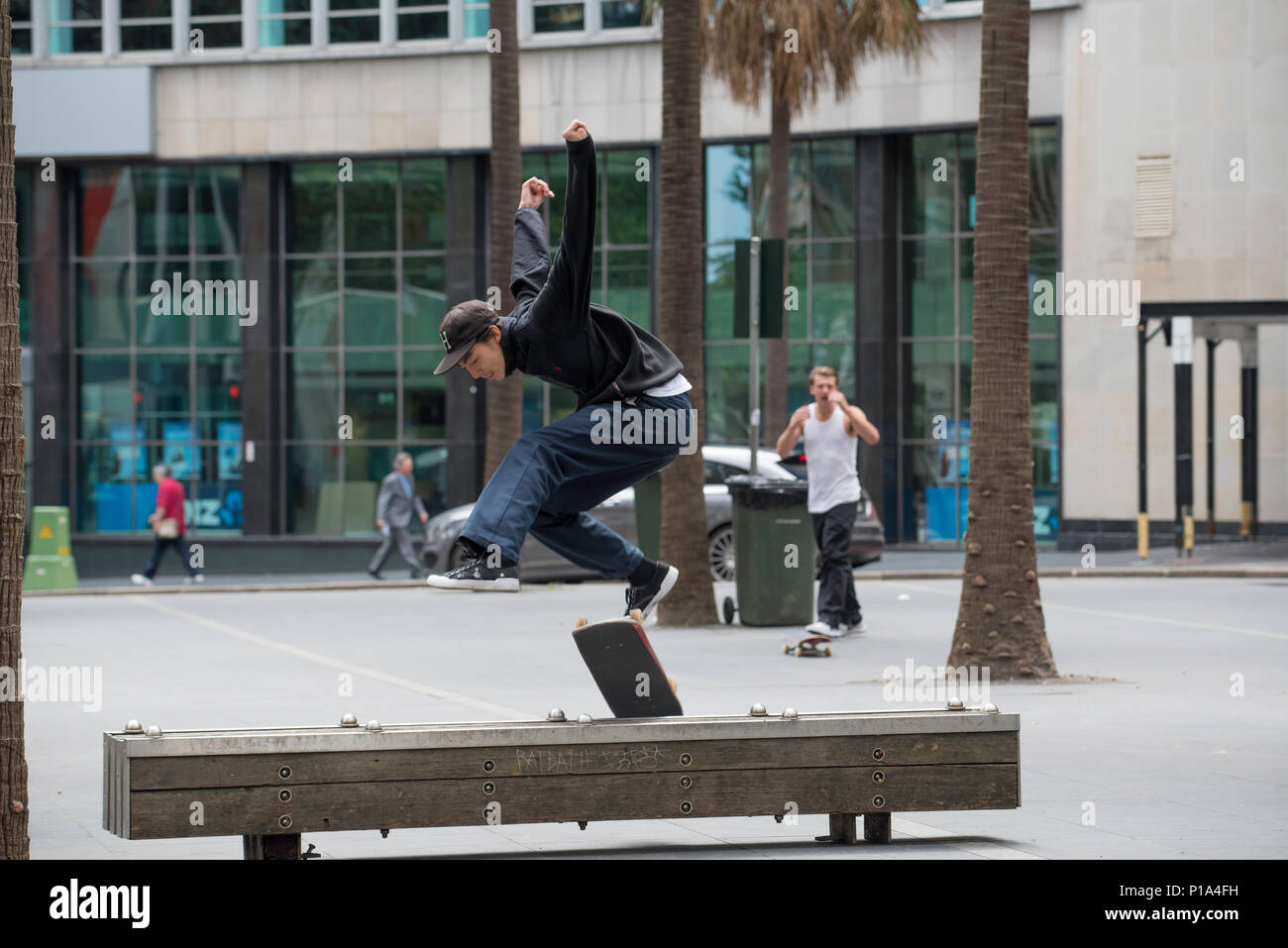 A skateboard rider performs a trick over a bench in Sydney city ...