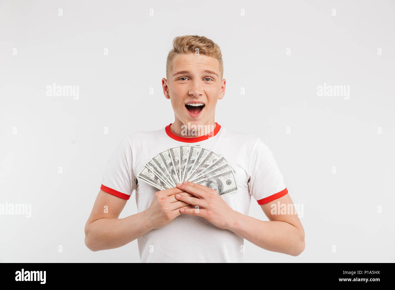 Portrait of a happy teenage boy holding money banknotes isolated over ...