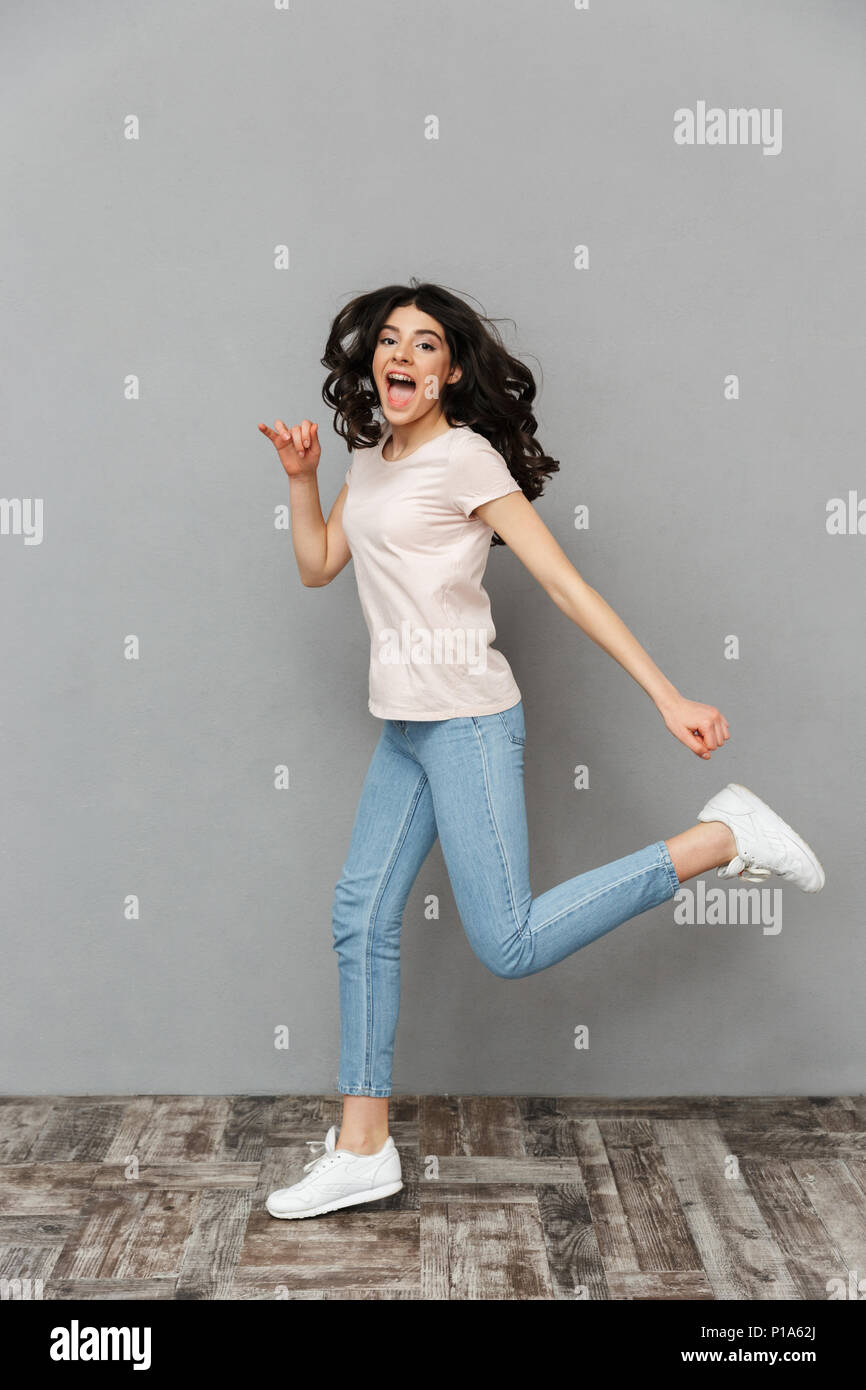 Image of beautiful young lady jumping isolated over grey background ...