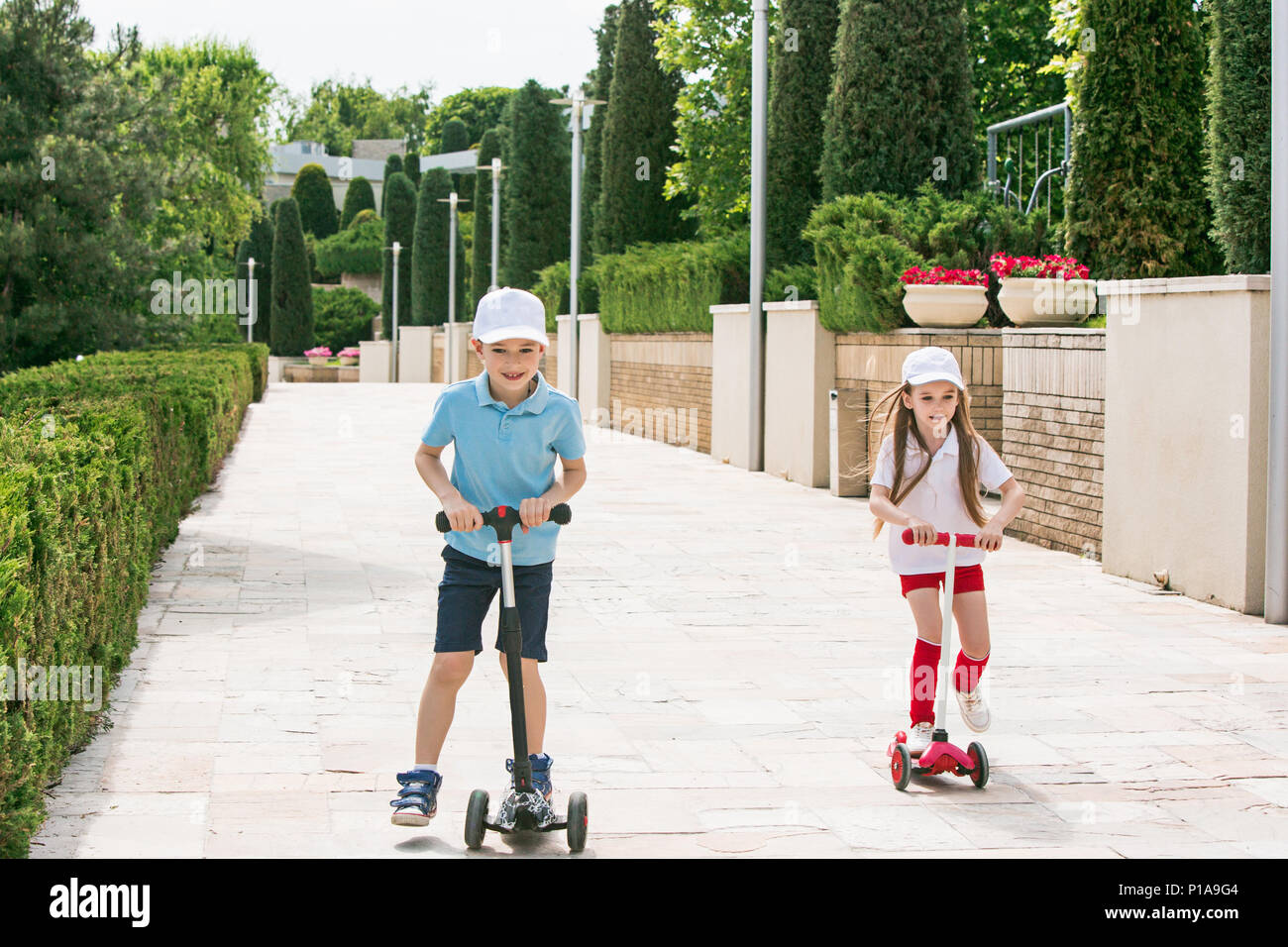 Preschooler girl and boy riding scooter outdoors Stock Photo - Alamy