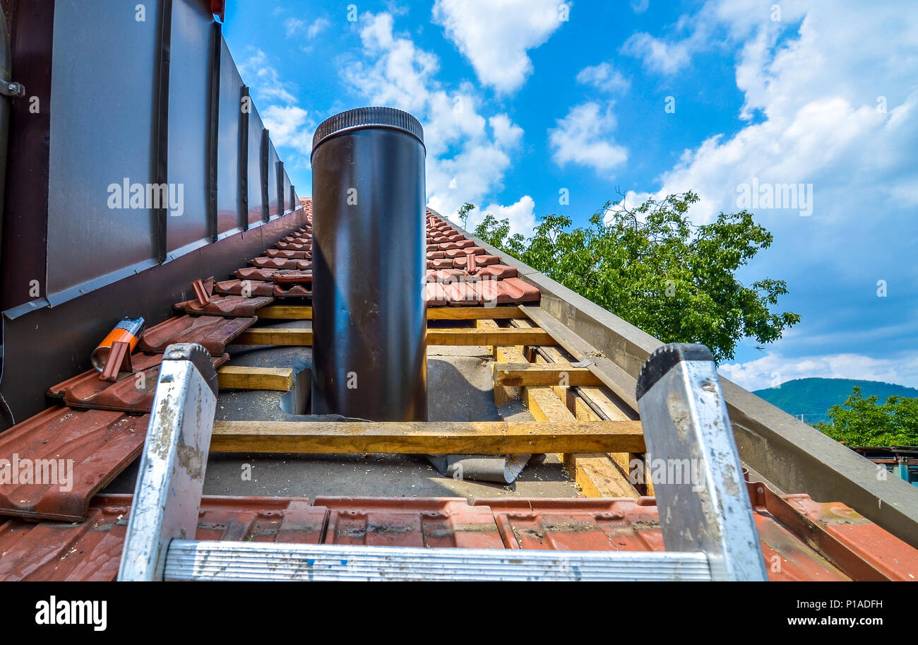 Installing external chimney trough a house roof with roof tiles ...