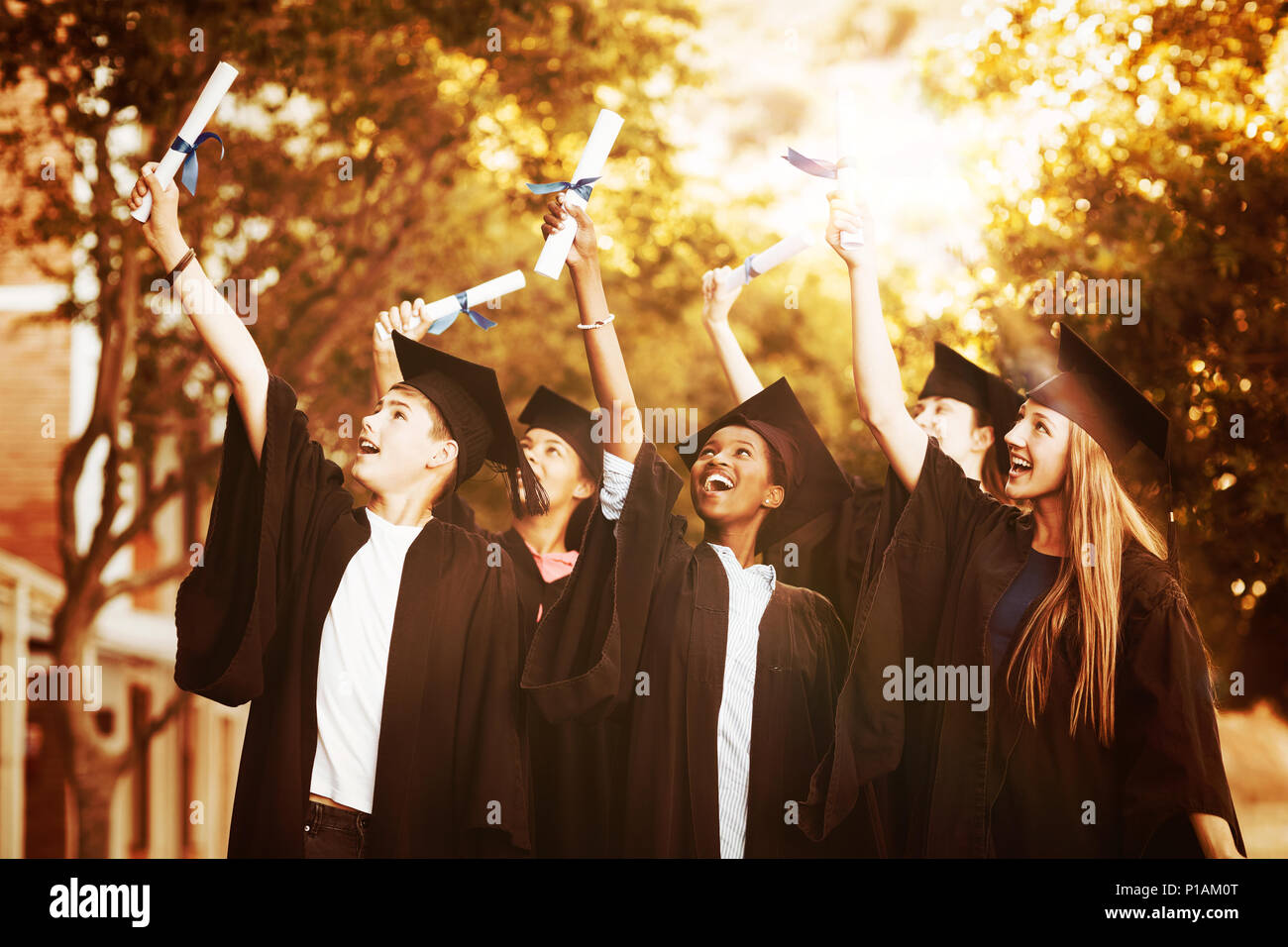 Smiling graduate school kids standing with degree scroll in campus ...