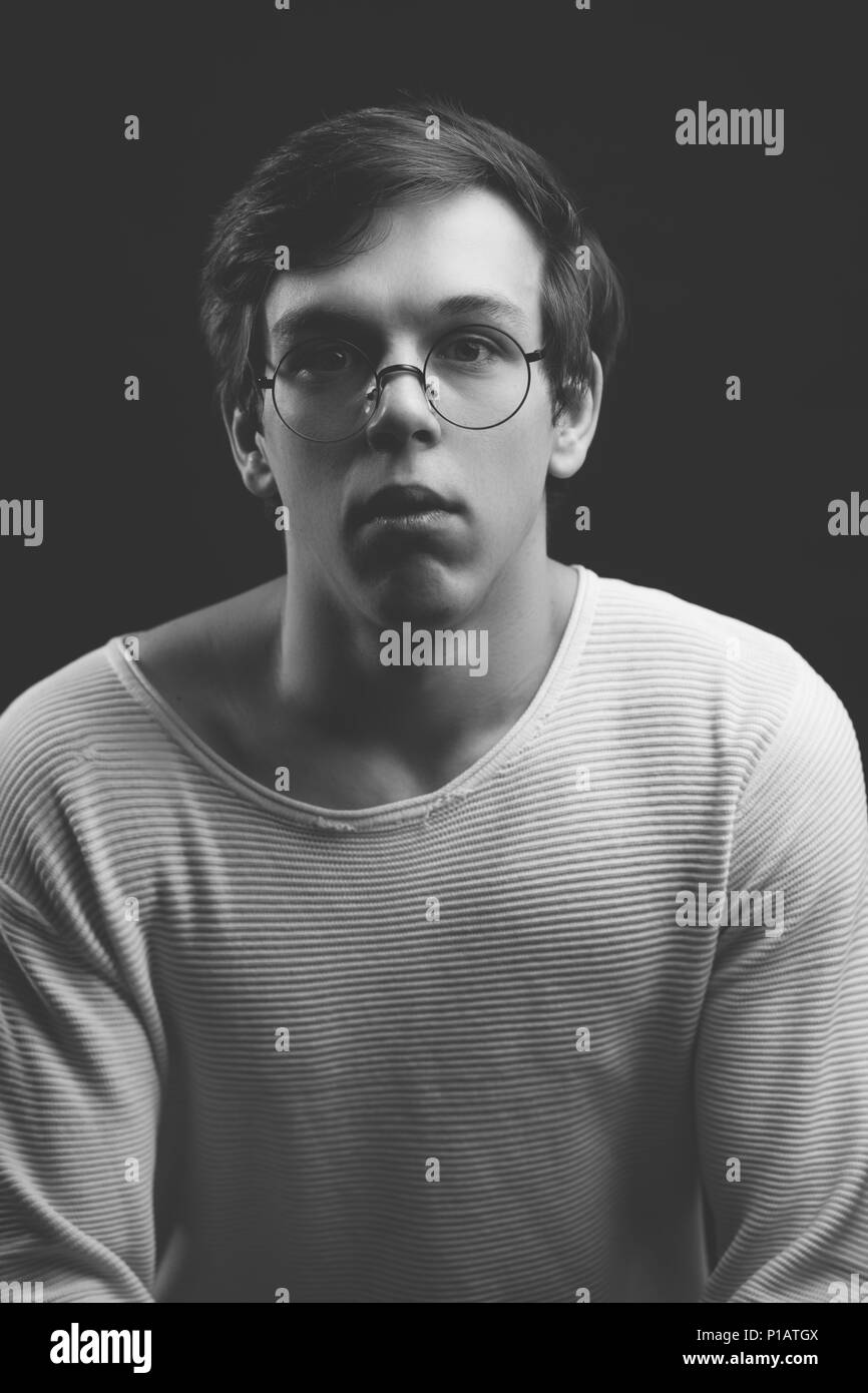 close up photo of pensive nerd in round glasses looking at the camera ...