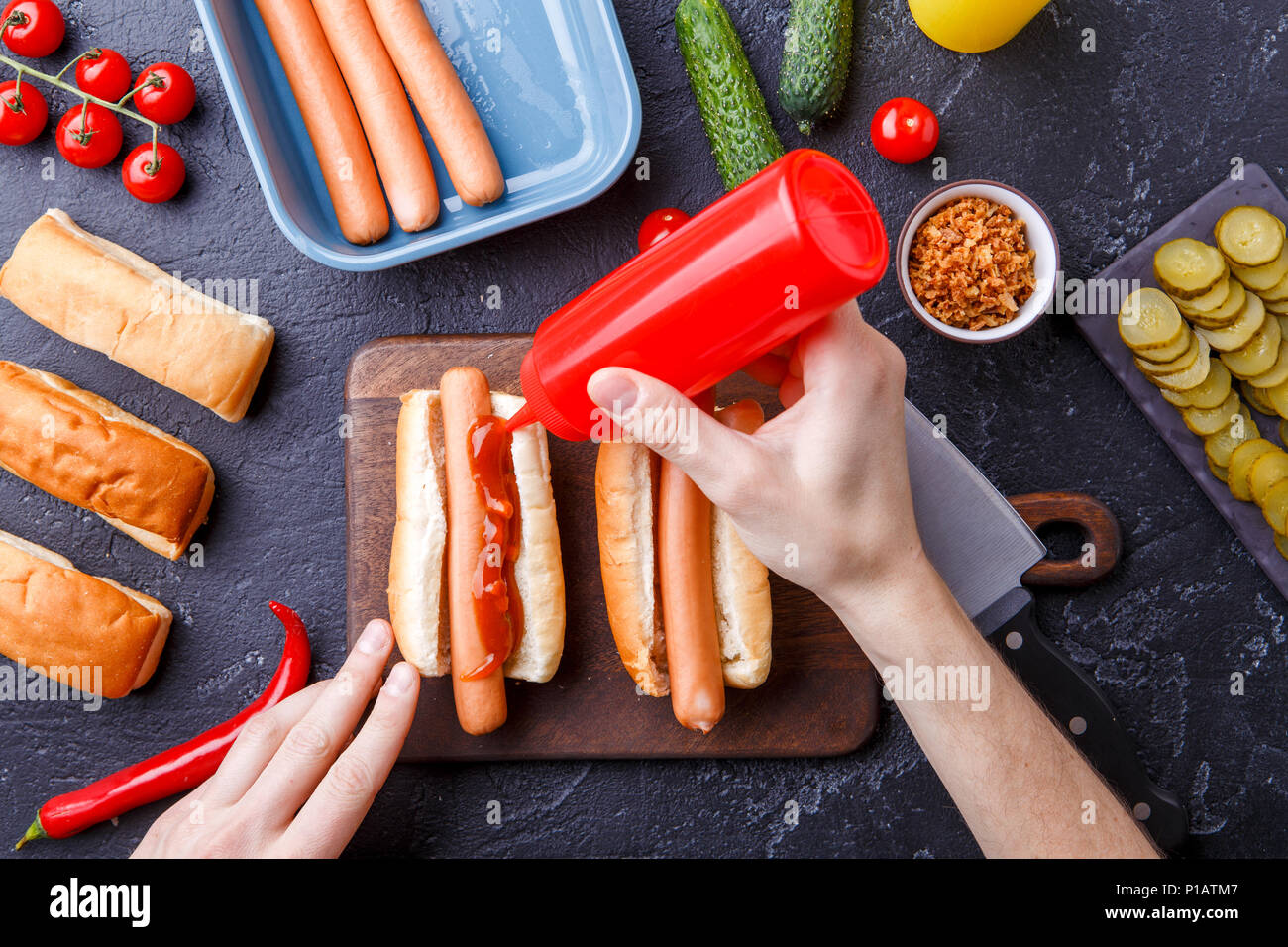 Picture on top of table with ingredients for hot dogs, cutting board ...
