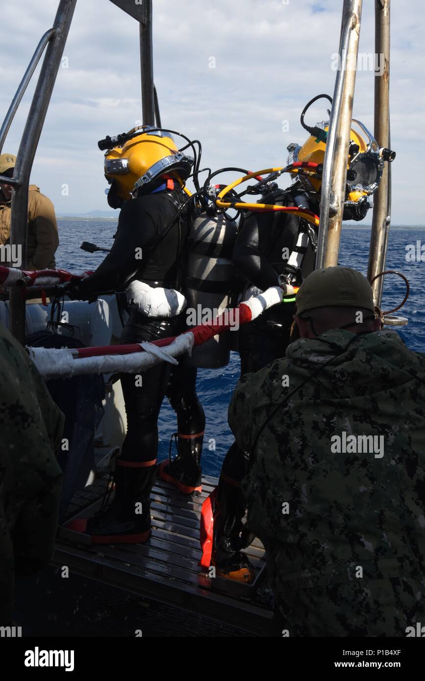U.S. Navy Divers of Mobile Diving and Salvage Unit 2 stand still to ...