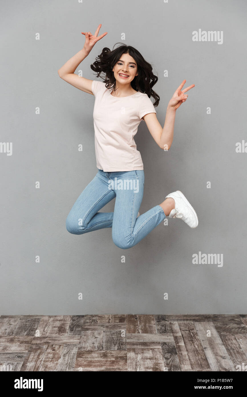 Photo of pretty cute young lady jumping isolated over grey background ...