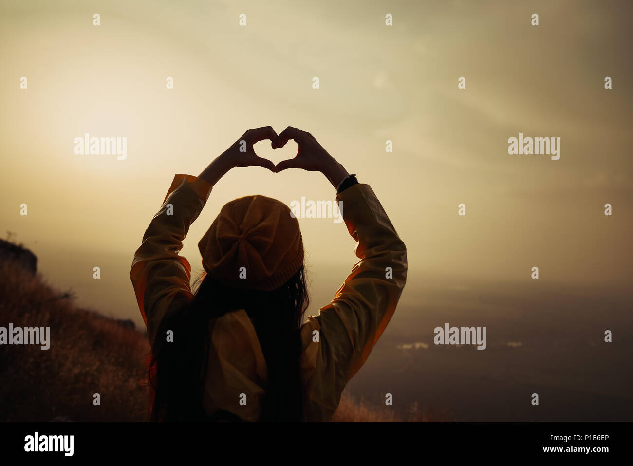 A young girl making heart symbol with her hands at sunset Stock Photo ...