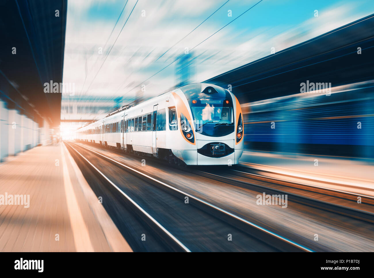 High speed passenger train in motion on the railway station at sunset ...
