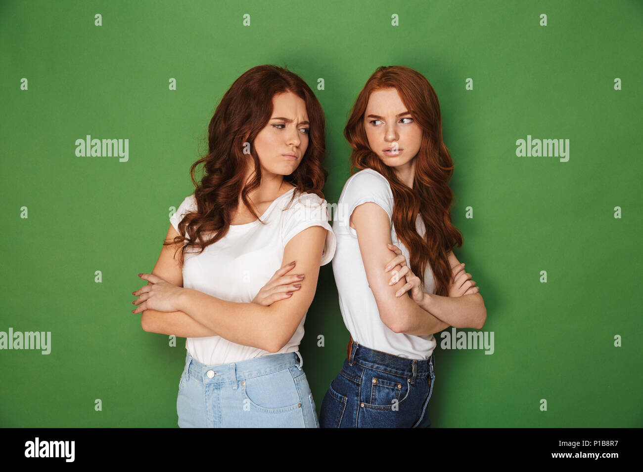 Two displeased girls 20s with ginger hair in casual wear standing back ...