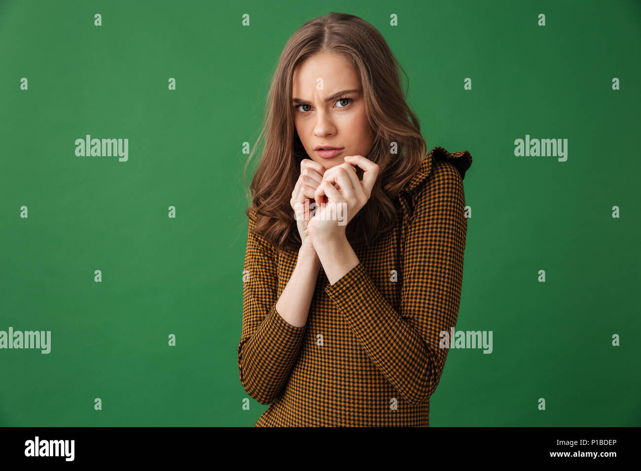 Image of scared young woman standing isolated over green background ...