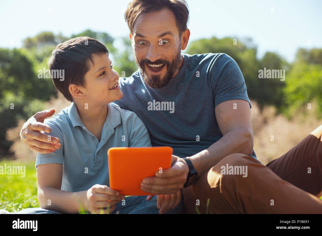 Surprised father watching a video with his son Stock Photo - Alamy