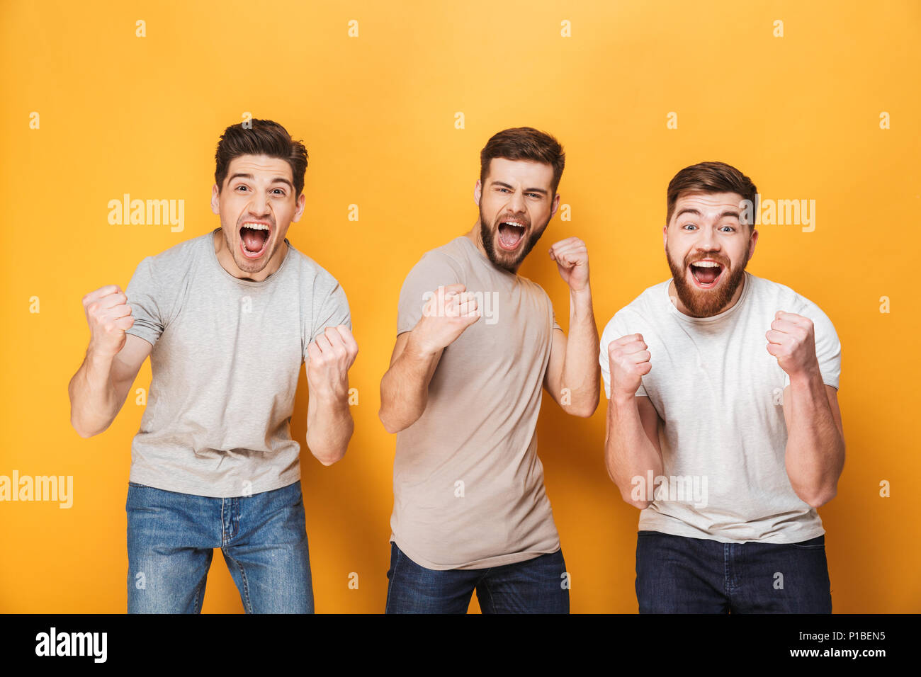 Three young excited men celebrating success together isolated over ...