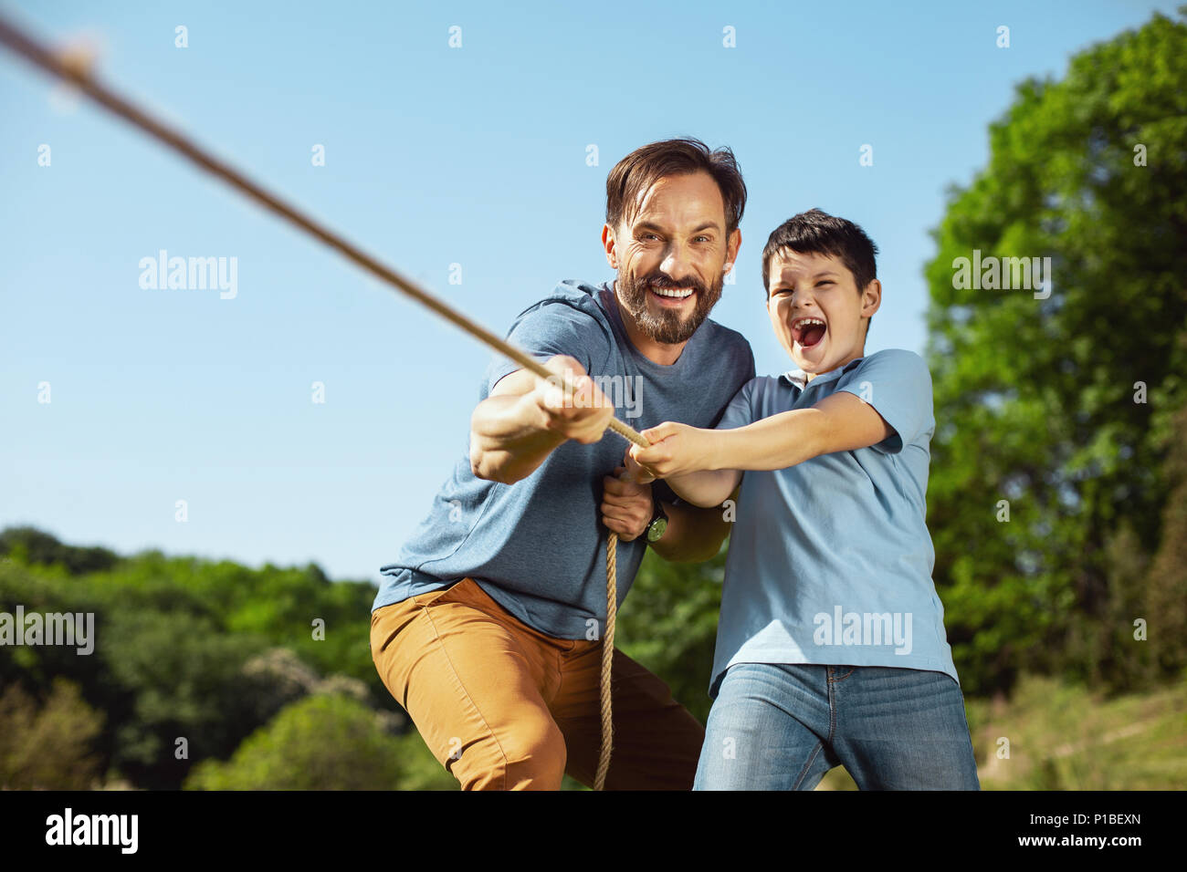 Happy family pulling a rope in the park Stock Photo - Alamy