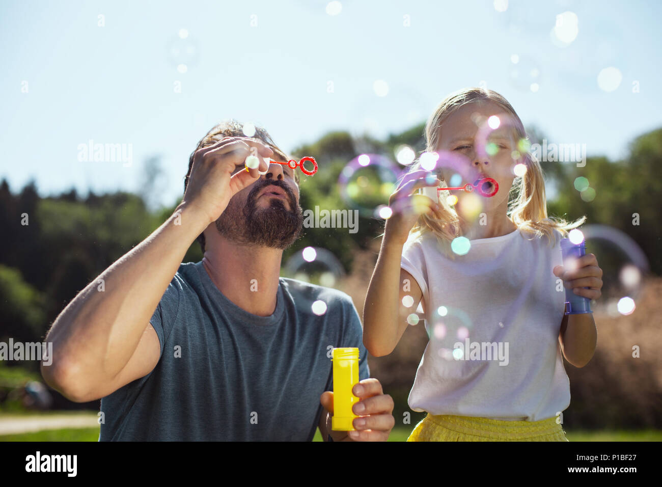 Content father blowing bubbles with his daughter Stock Photo - Alamy