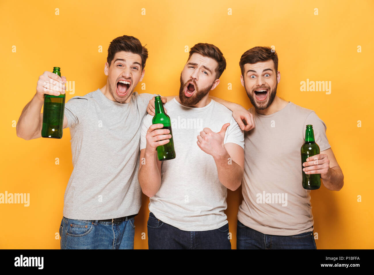 Three young cheerful men holding beer and celebrating isolated over ...