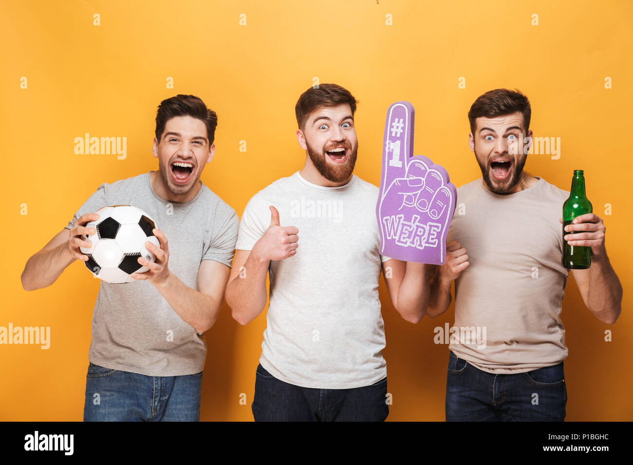 Three young excited men football fans celebrating isolated over yellow ...