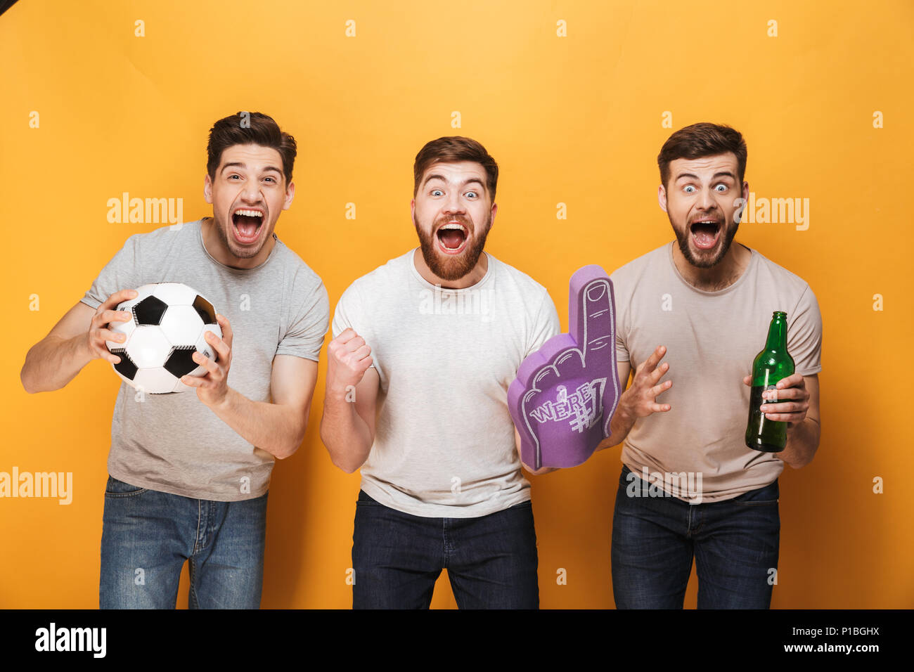 Three young happy men football fans celebrating isolated over yellow ...