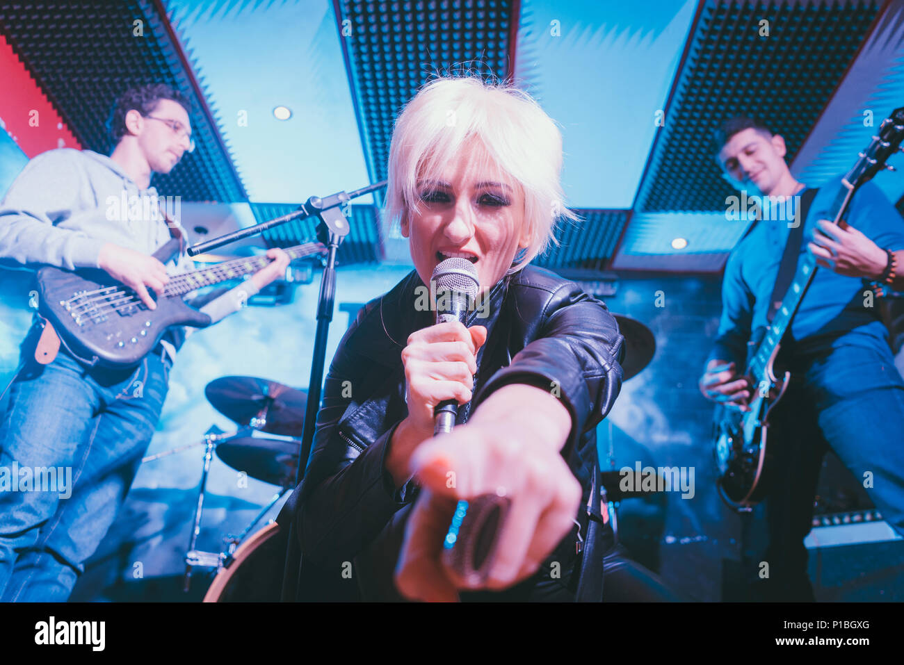 Band during gig making rock music on stage Stock Photo - Alamy