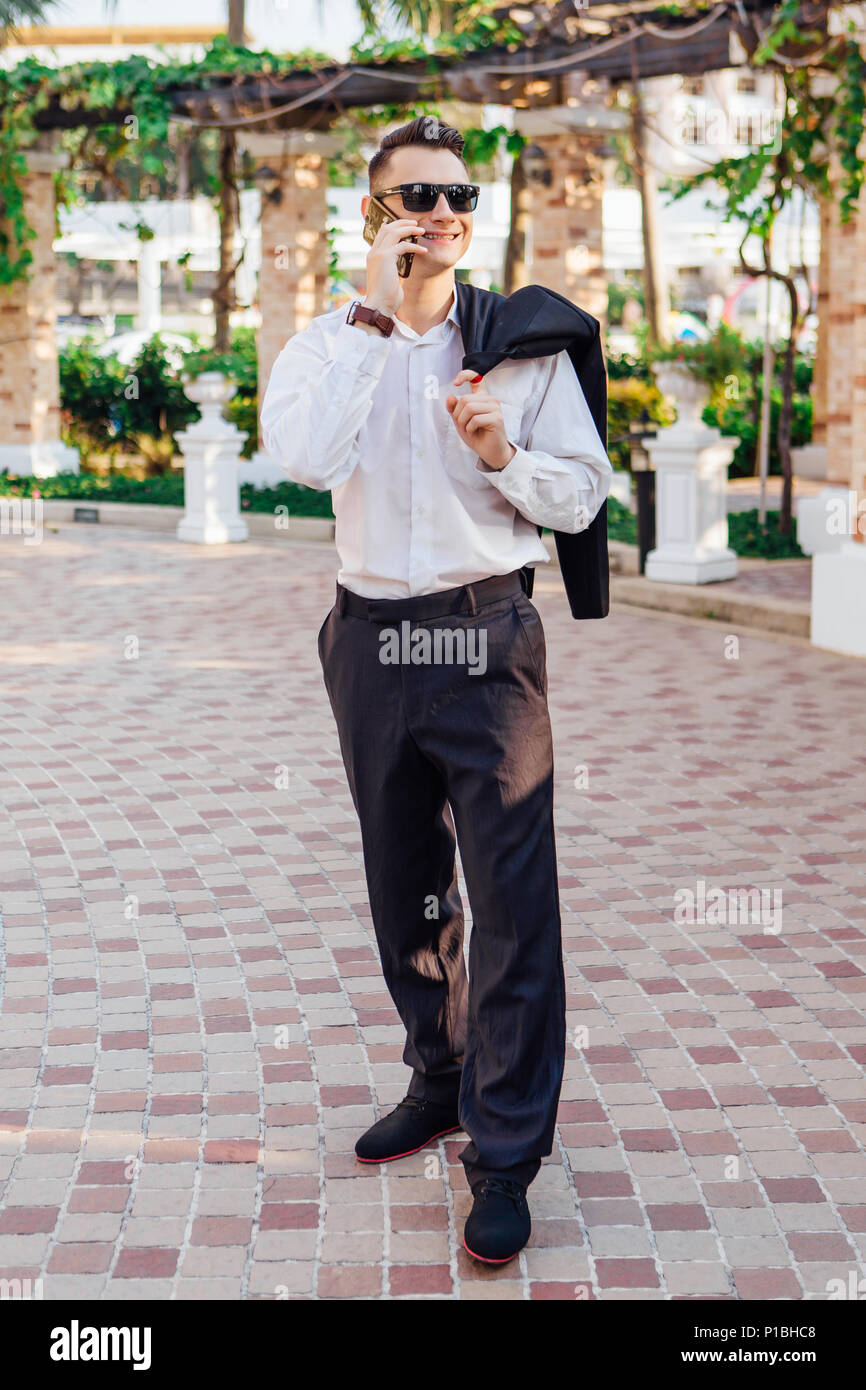 Young businessman talking on his phone outdoors in a tropical country ...