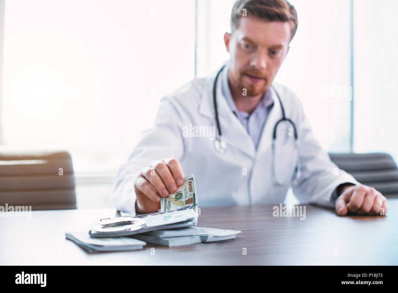 Skilled doctor taking bribes in his office Stock Photo - Alamy