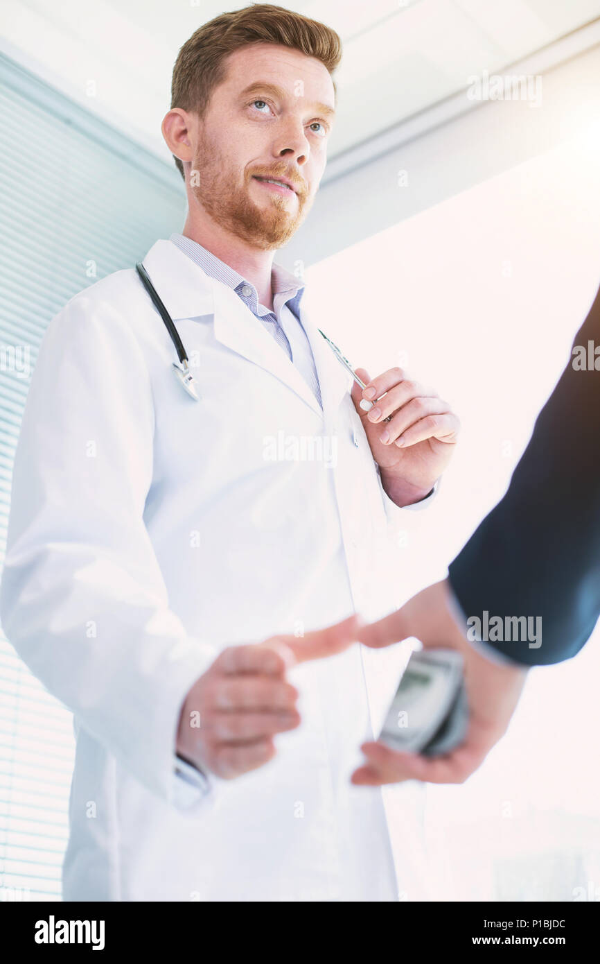Joyful doctor taking a bribe for operation Stock Photo - Alamy