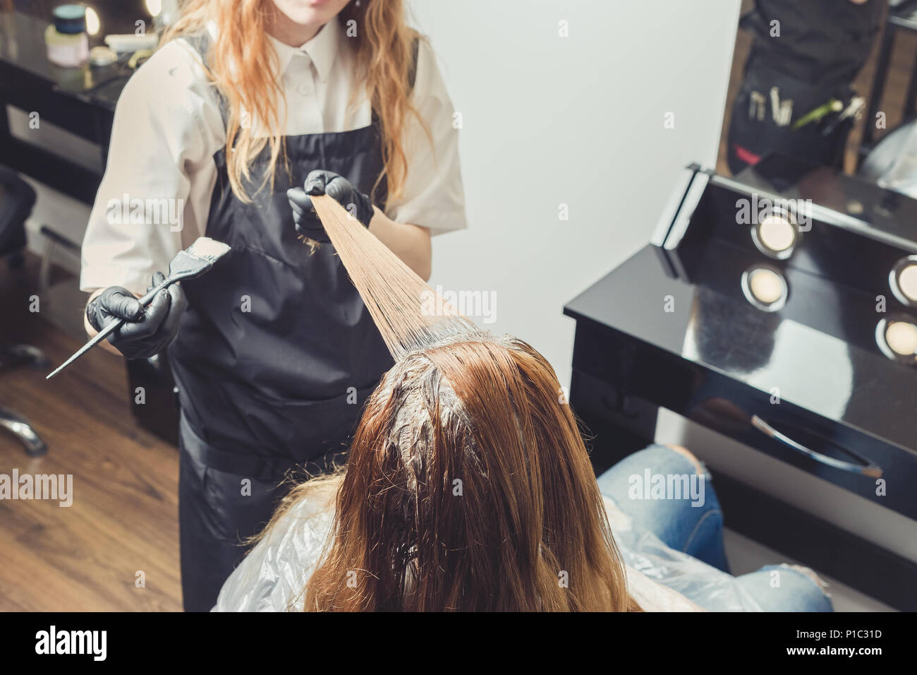Female stylist applying a dye to the clients hair at beauty salon Stock ...