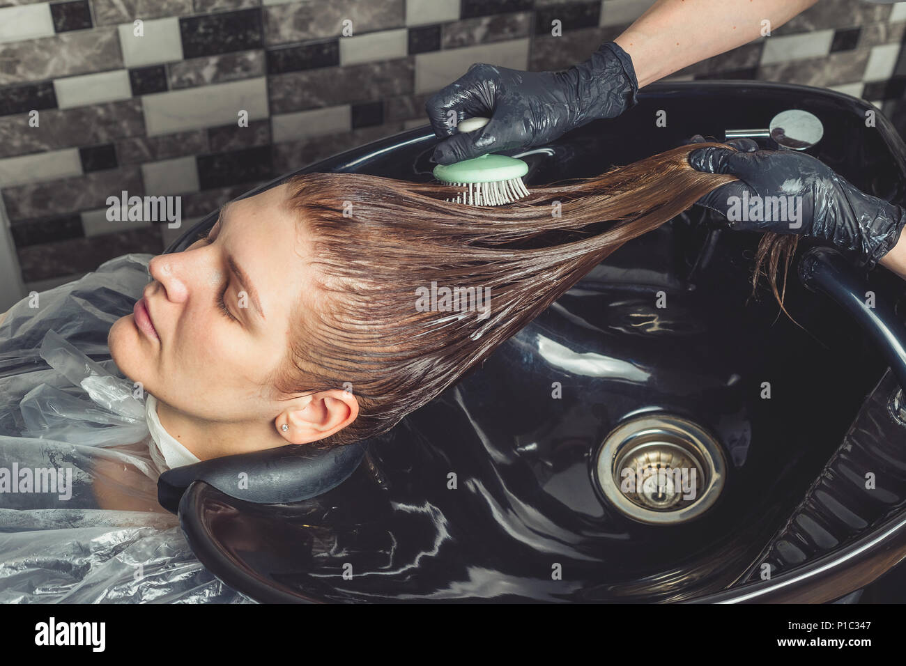 Haircare procedure in beauty salon. Hairdresser is brushing woman's ...