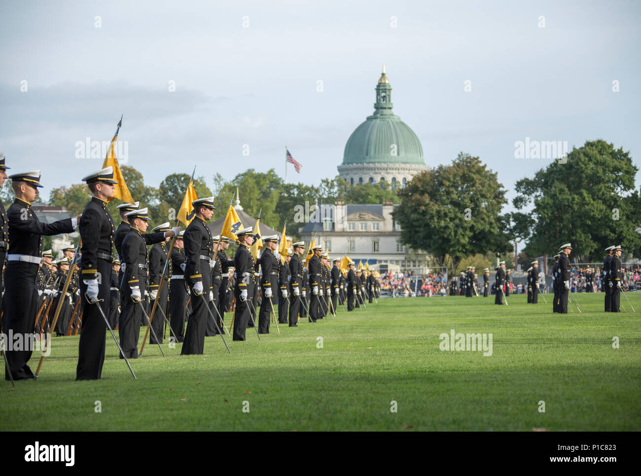 Midshipmen with the U.S. Naval Academy (USNA) stand at parade rest ...