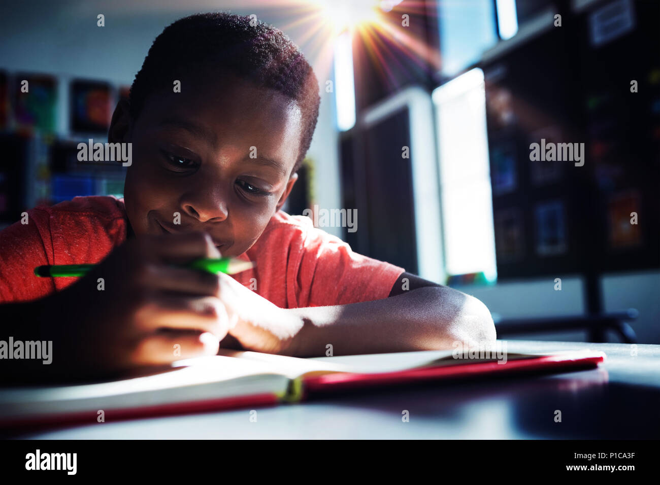 Boy writing in book Stock Photo - Alamy