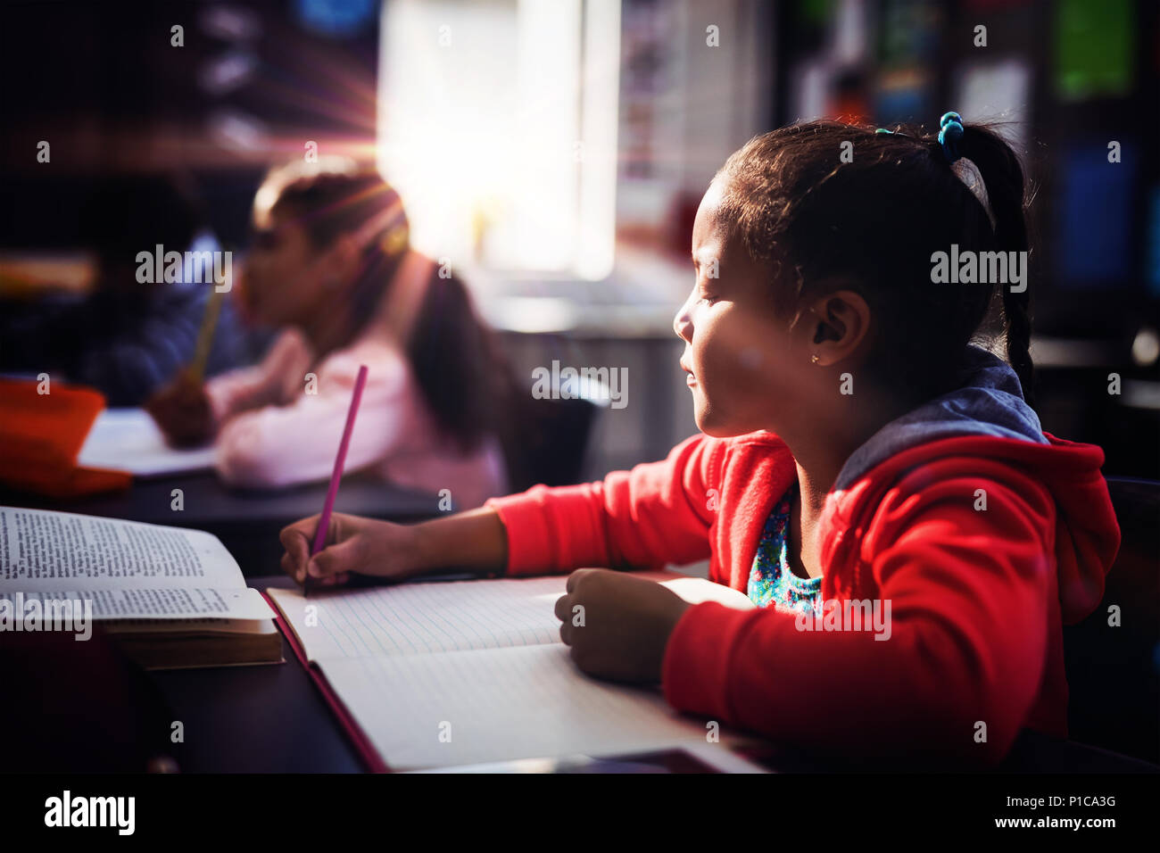 Attentive schoolgirl doing her homework in classroom Stock Photo - Alamy