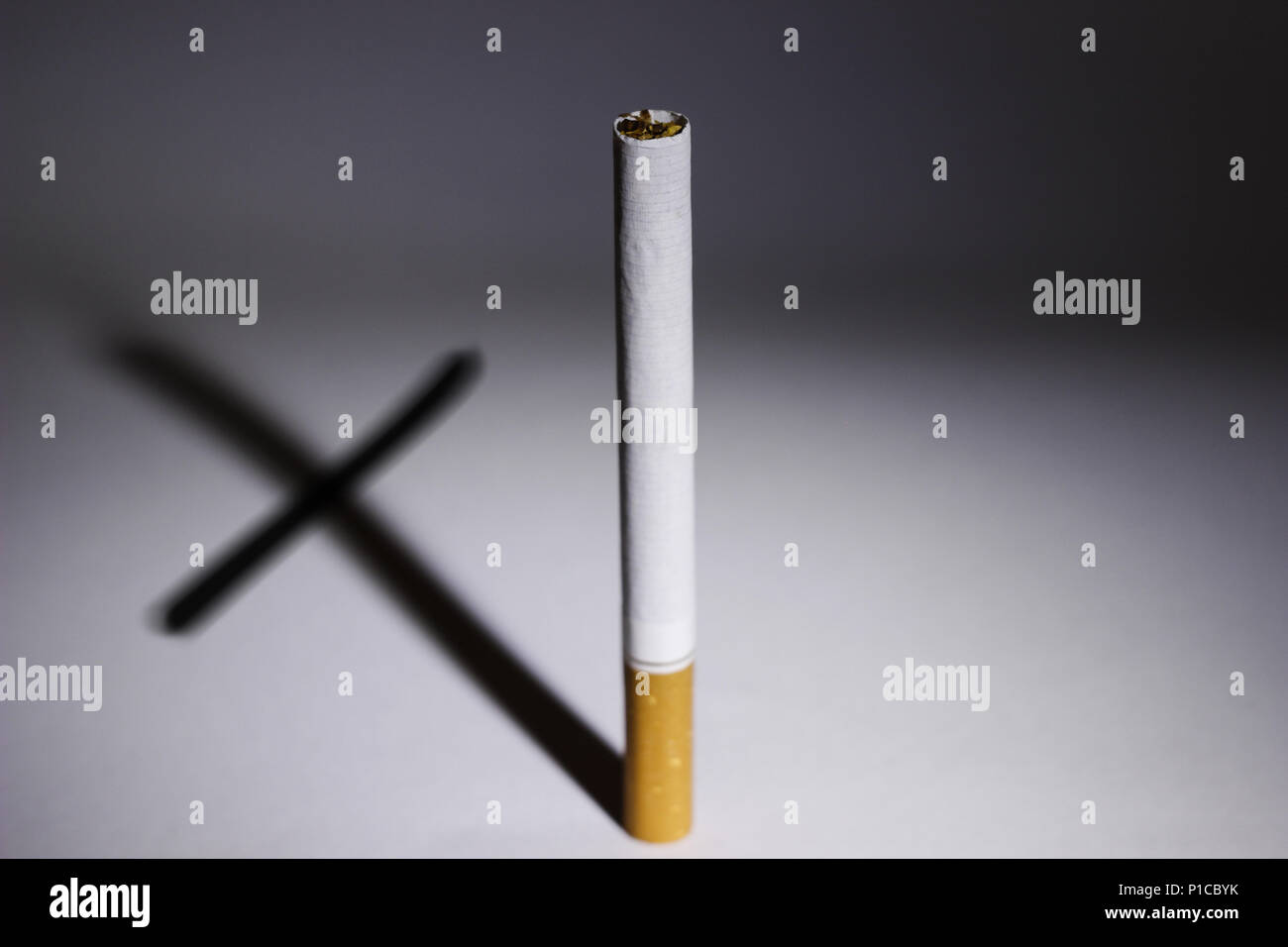 A frontal close up of a cigarette throwing a shadow in a cross shape ...