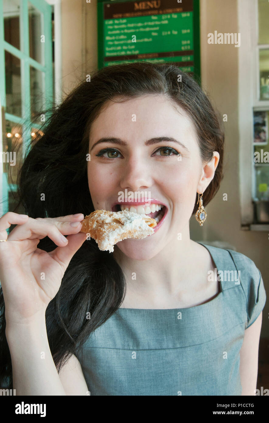 A woman eating a beignet at Cafe du Monde in New Orleans, Louisiana ...