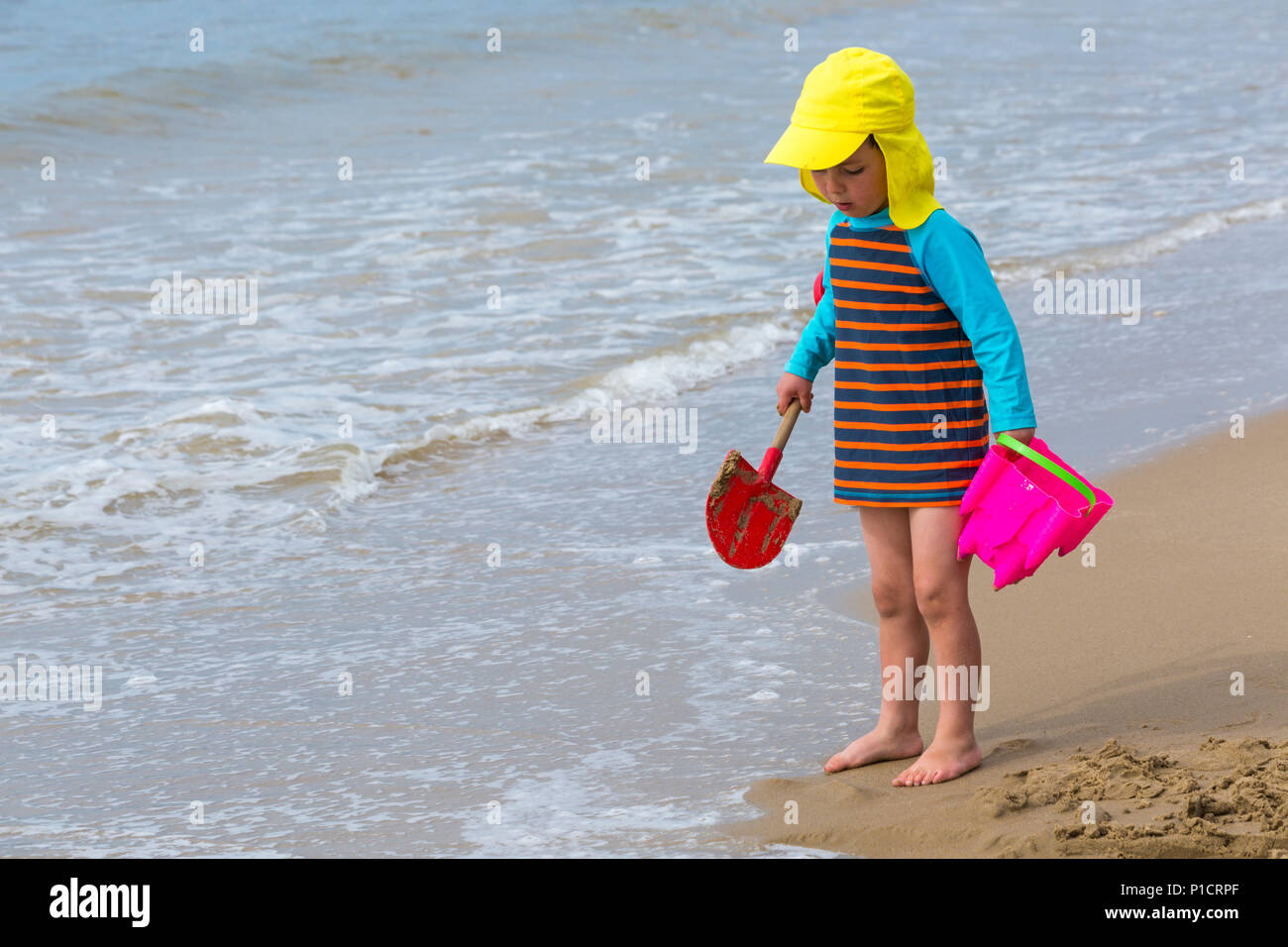 Boy playing with bucket and spade in the sand hi-res stock photography ...