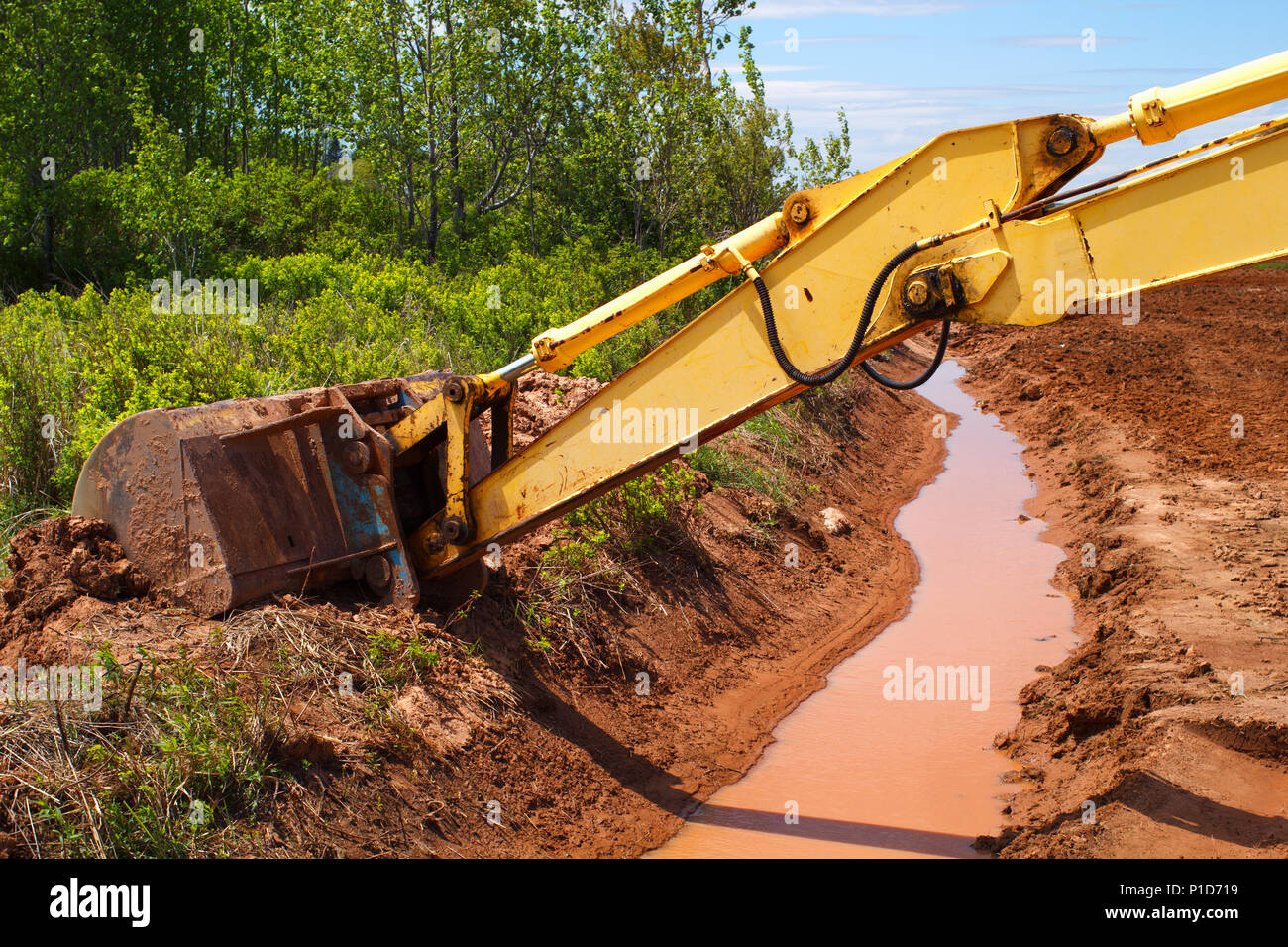 Excavator bucket and hydraulic arm extended over a muddy ditch Stock ...