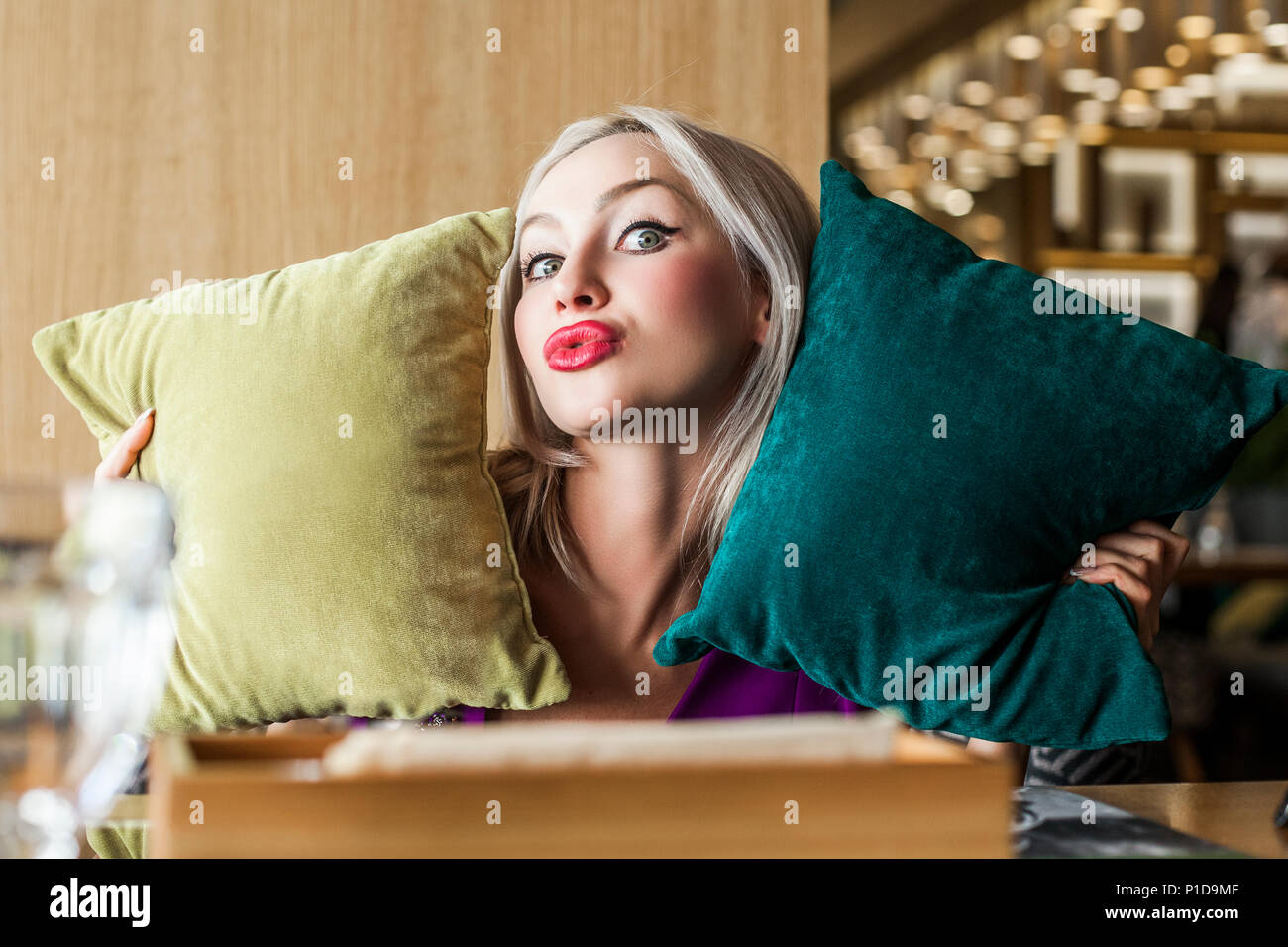 Cute woman with pillows. Female model with blonde hair on background ...