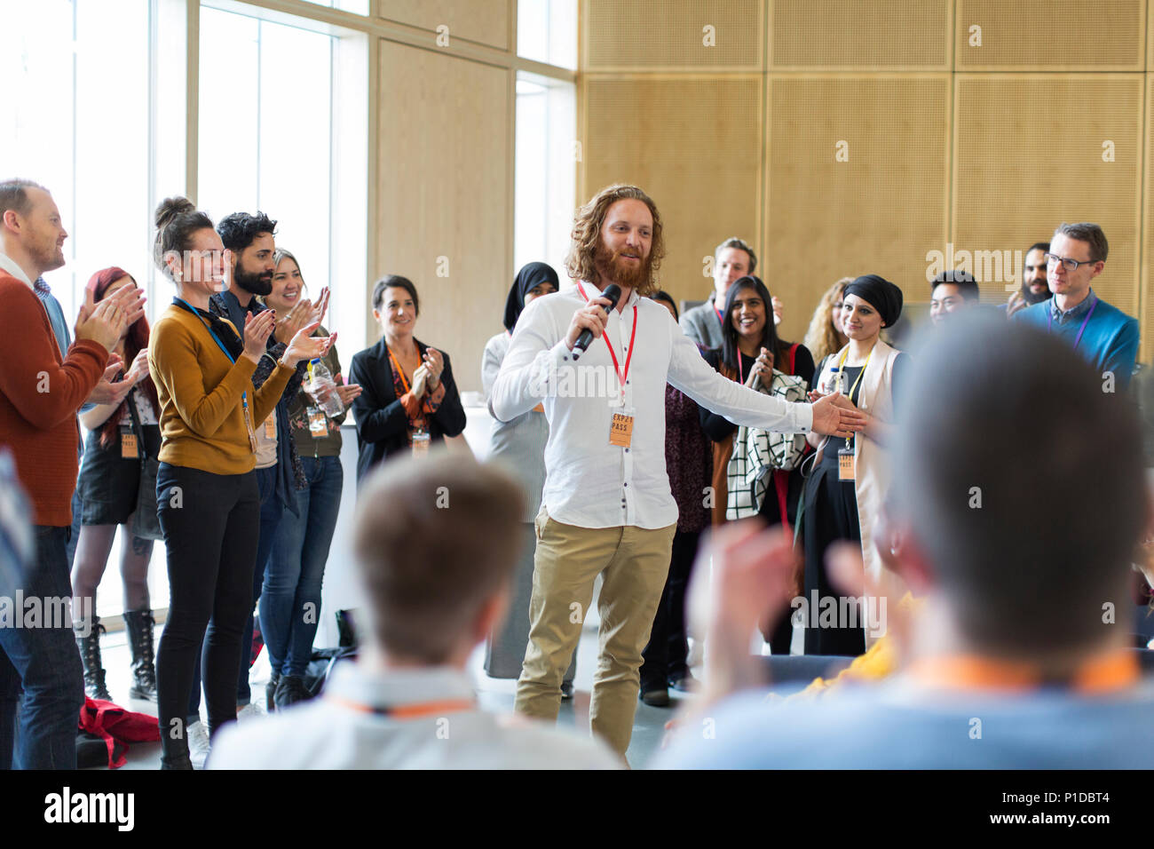 Conference audience clapping for businessman speaker with microphone ...