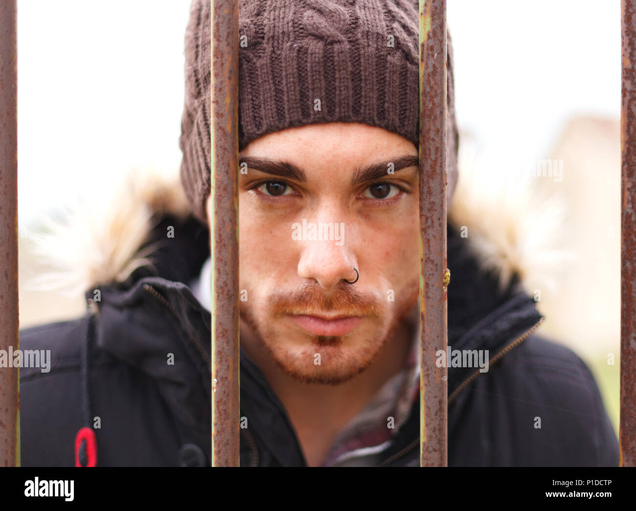 Attractive guy behide the bars with wool hat Stock Photo - Alamy