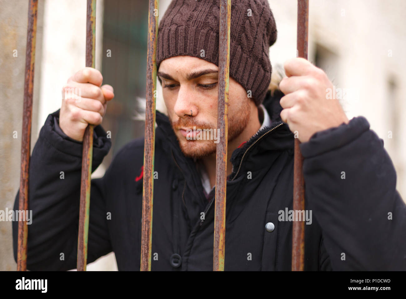 Attractive guy behide the bars with wool hat Stock Photo - Alamy