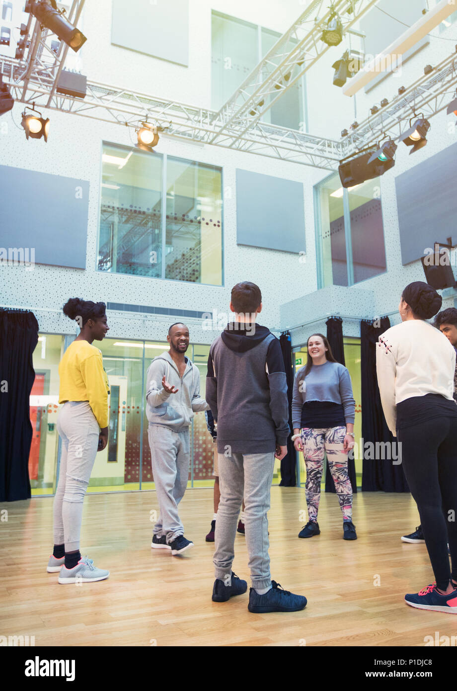 Teenage students listening to male instructor in dance class studio ...