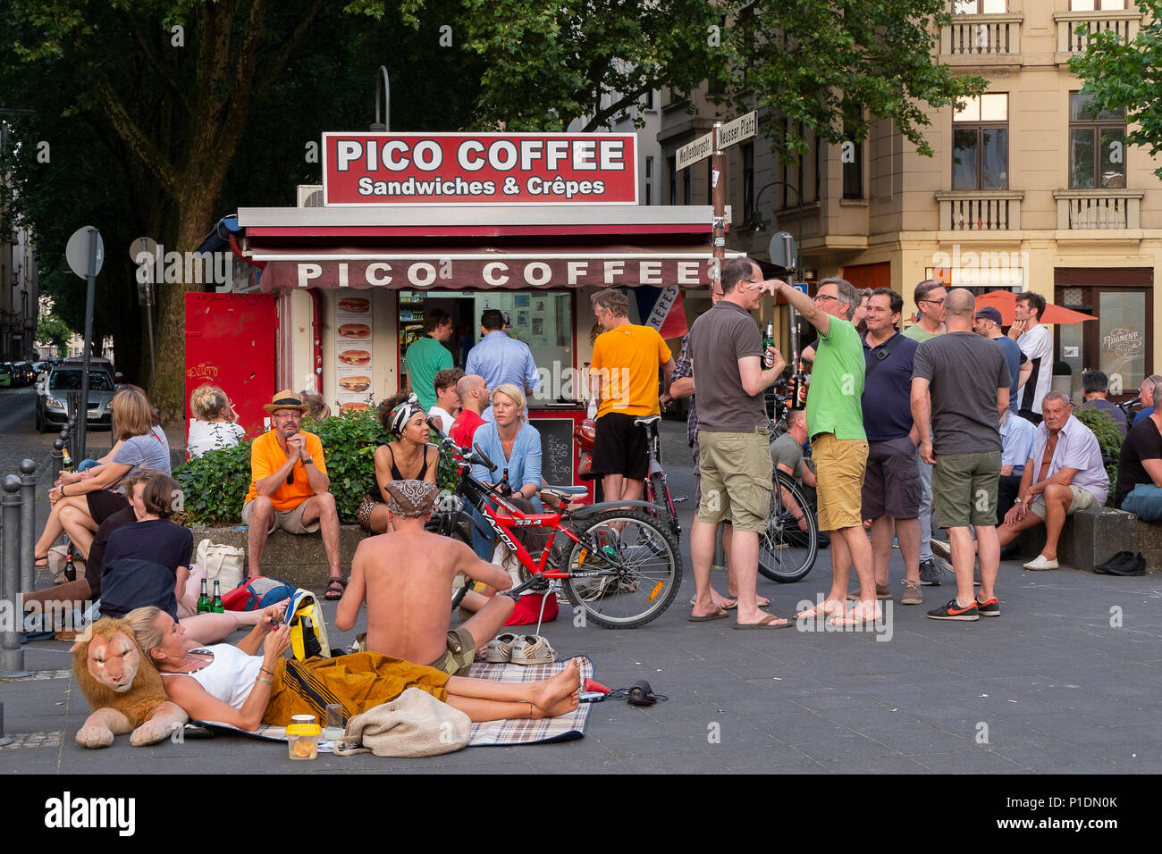 People buying drinks at a refreshment kiosk and drinking in the street ...