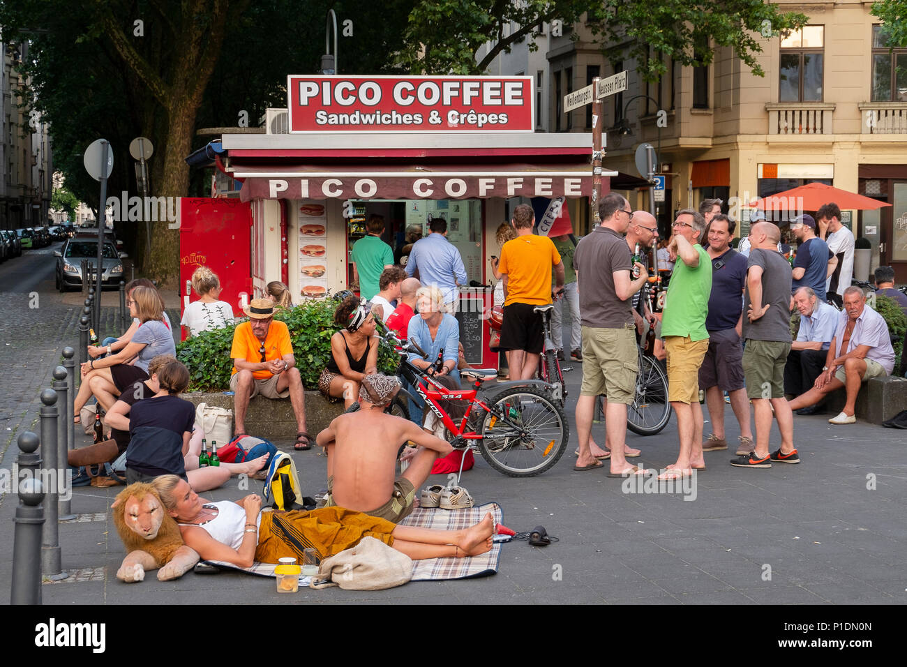 People buying drinks at a refreshment kiosk and drinking in the street ...