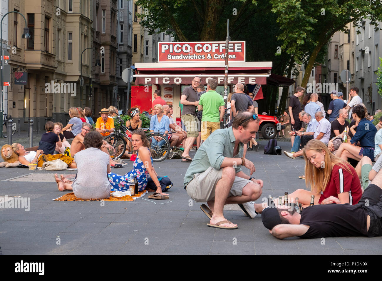 People buying drinks at a refreshment kiosk and drinking in the street ...
