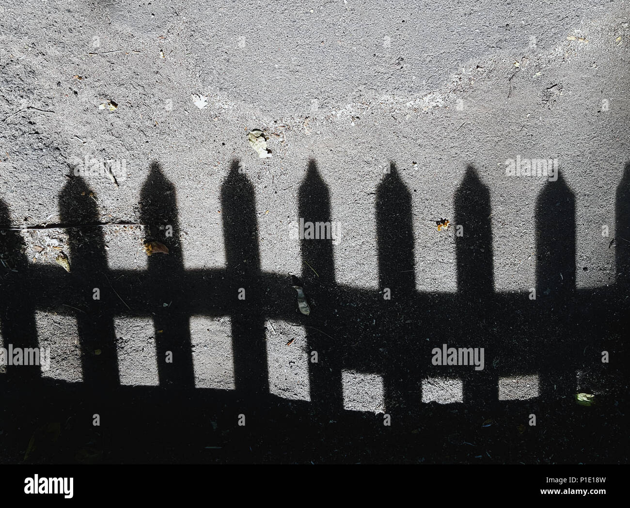 Black shadow from a low fence on a gray light asphalt Stock Photo - Alamy