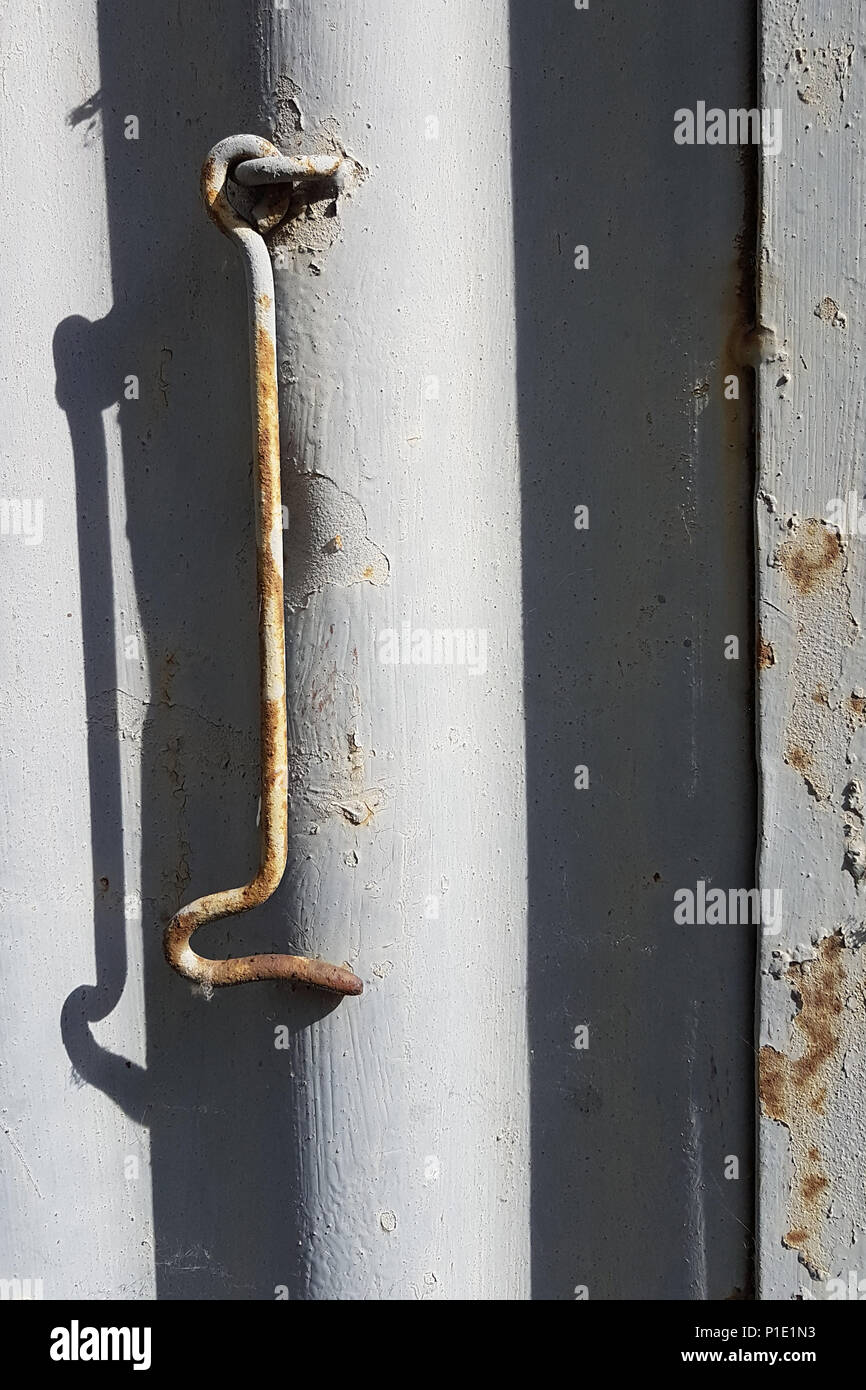 Metal door hook for closing a door on a metal striped background ...