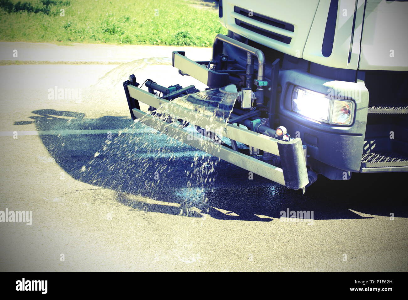 Large roadwashing truck while spraying water on the asphalt Stock Photo ...