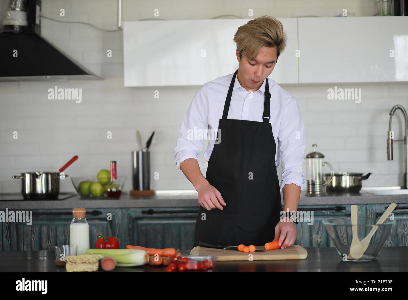 A young Asian cook in the kitchen prepares food in a cook suit Stock ...