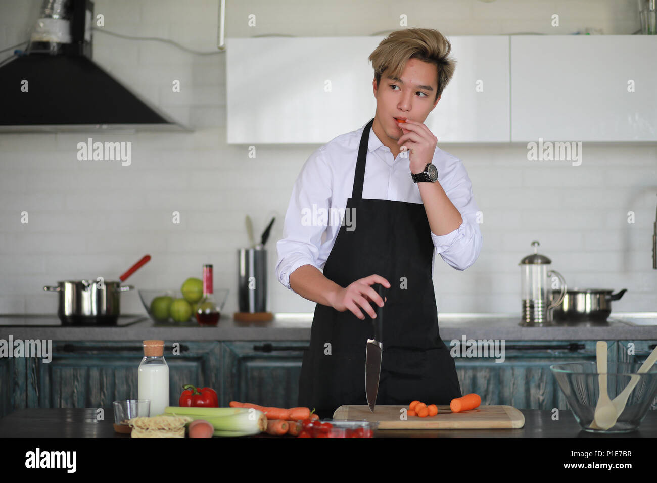 A young Asian cook in the kitchen prepares food in a cook suit Stock ...