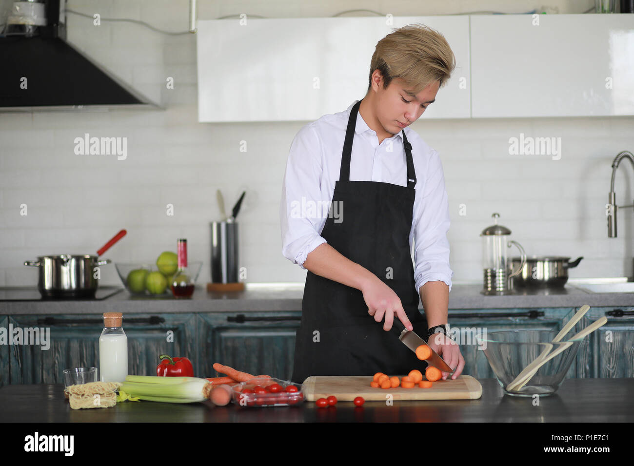 A young Asian cook in the kitchen prepares food in a cook suit Stock ...